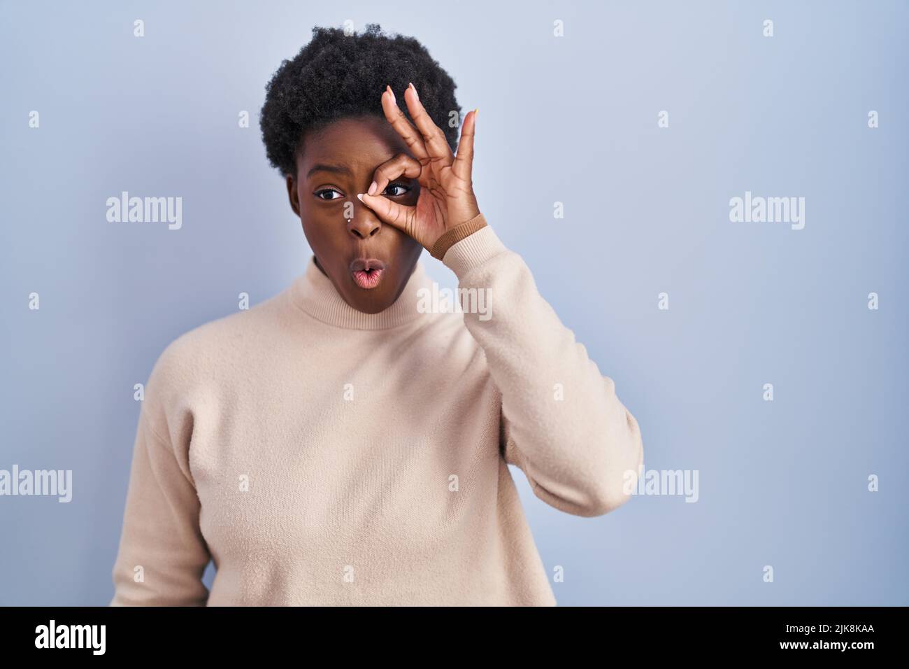 African american woman standing over blue background doing ok gesture ...