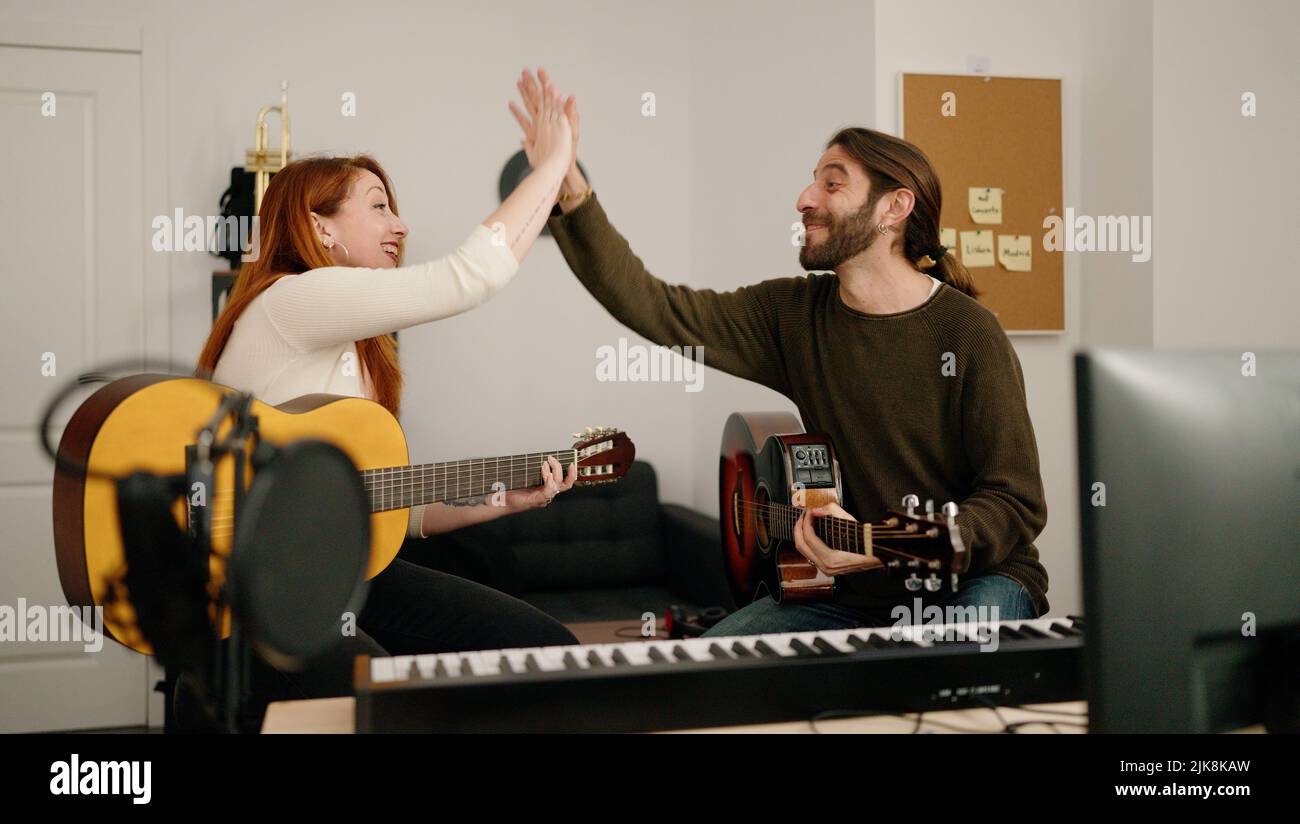 Man and woman playing guitar high five at music studio Stock Photo - Alamy