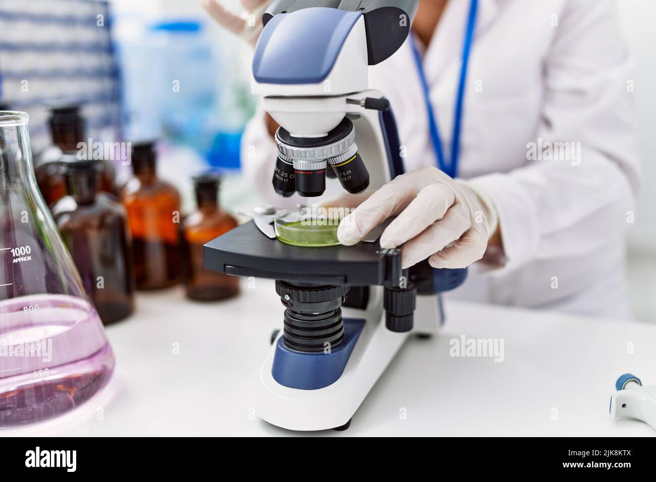 Senior grey-haired woman wearing scientist uniform using microscope at ...