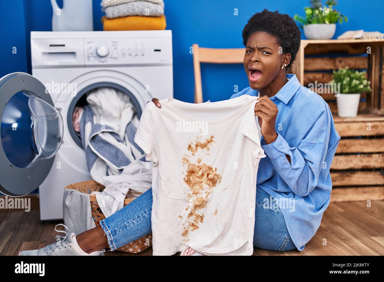 African american woman holding t shirt with dirty stain angry and mad ...