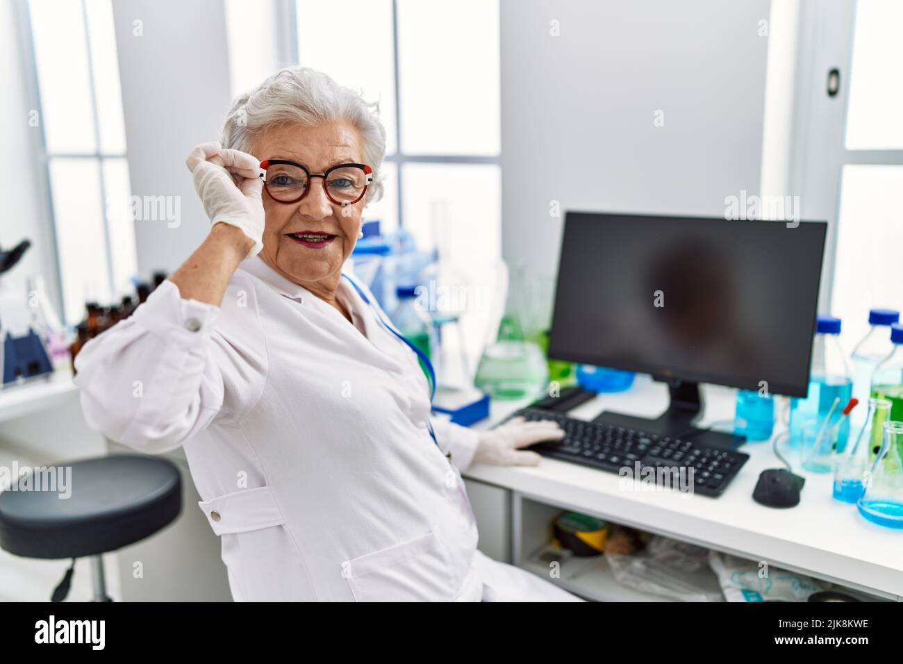 Senior grey-haired woman wearing scientist uniform using computer ...