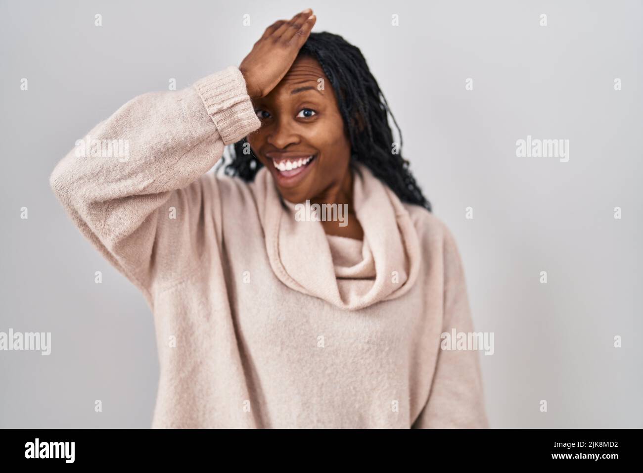 African woman standing over white background surprised with hand on ...