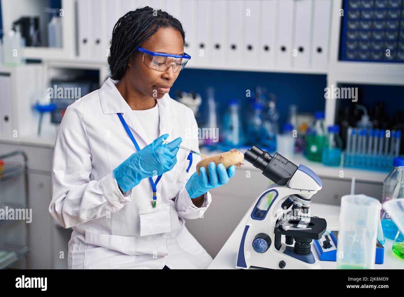 African american woman wearing scientist injecting on potato laboratory ...