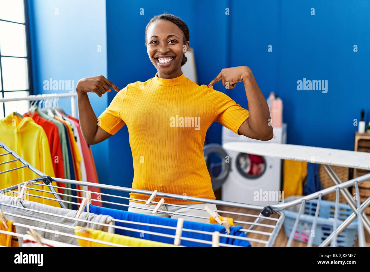 African woman hanging clothes at clothesline looking confident with ...