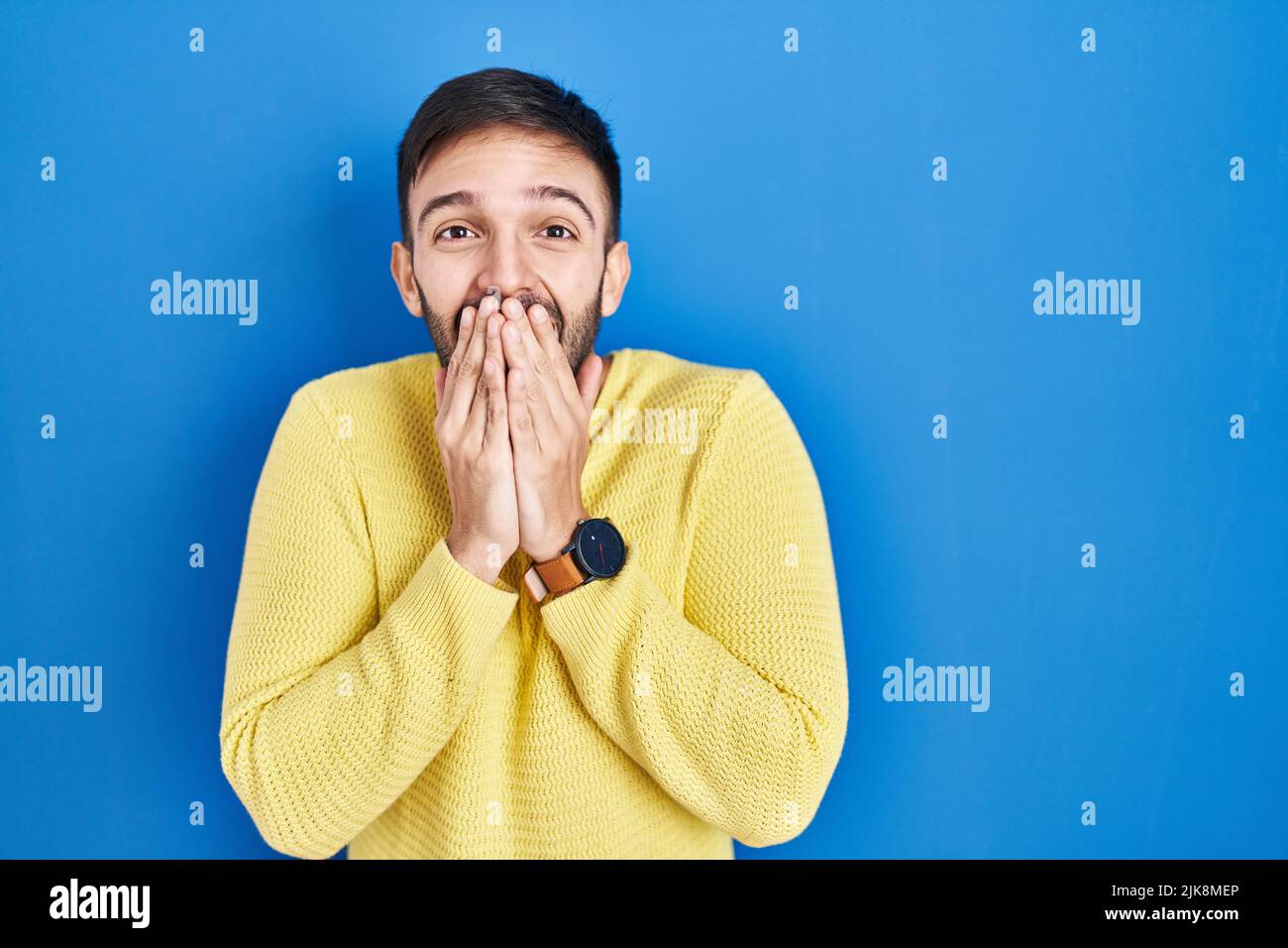Hispanic man standing over blue background laughing and embarrassed ...