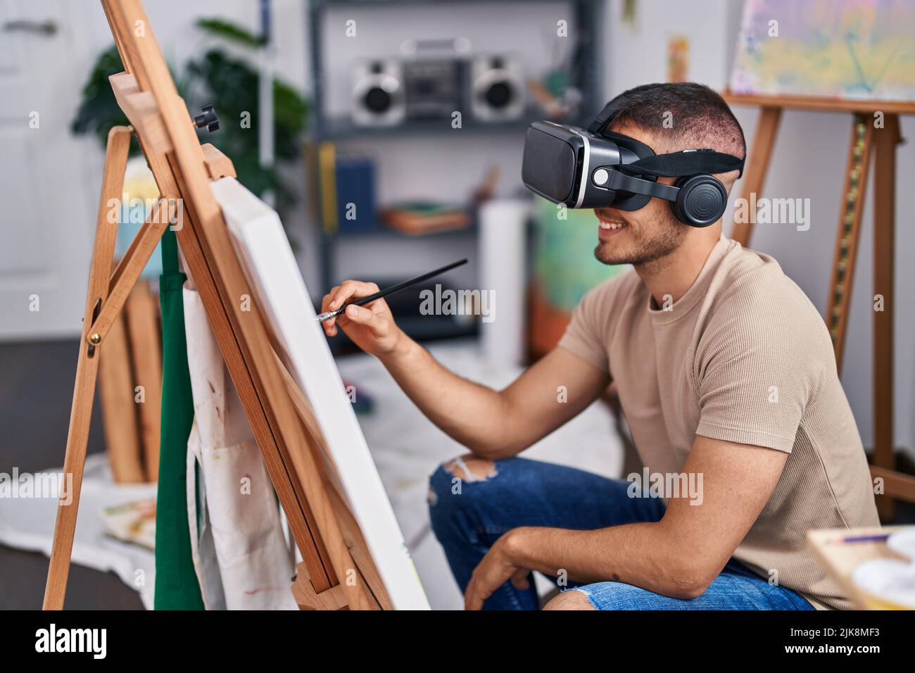 Young hispanic man artist using virtual reality glasses drawing at art ...