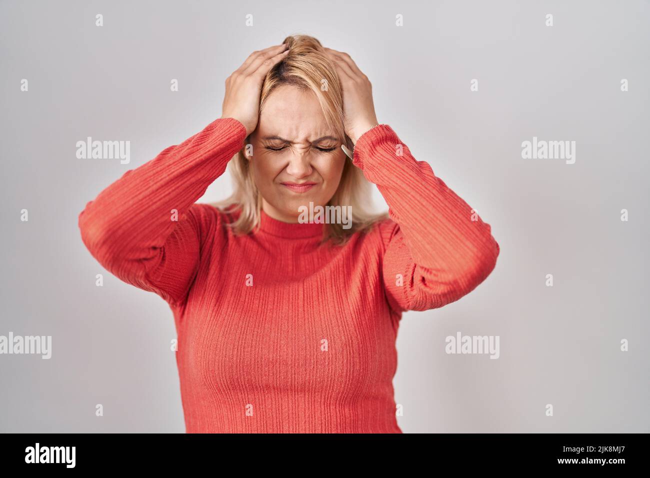Blonde woman standing over isolated background suffering from headache ...