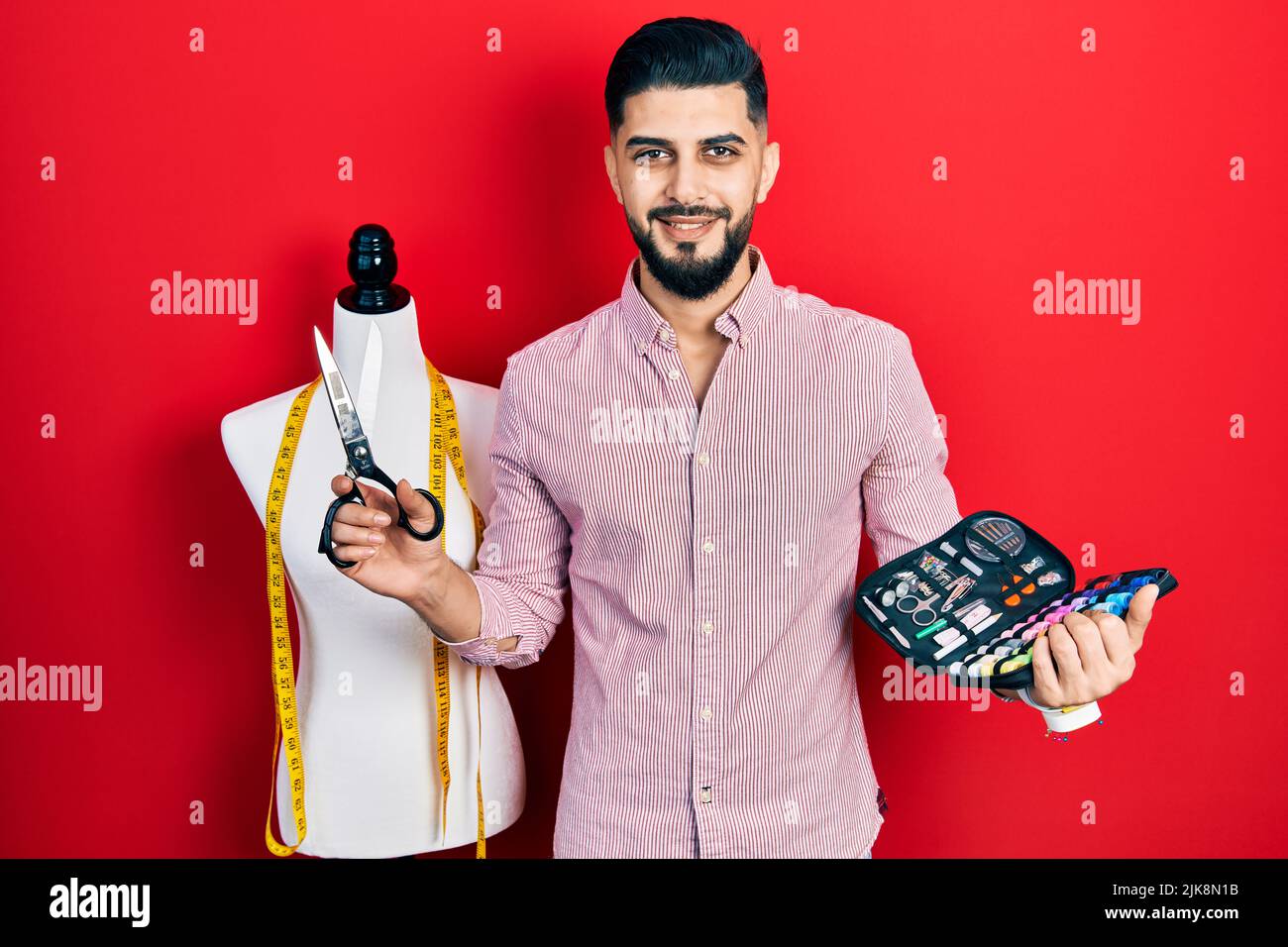 Handsome tailor man with beard holding sew kit and scissors smiling ...