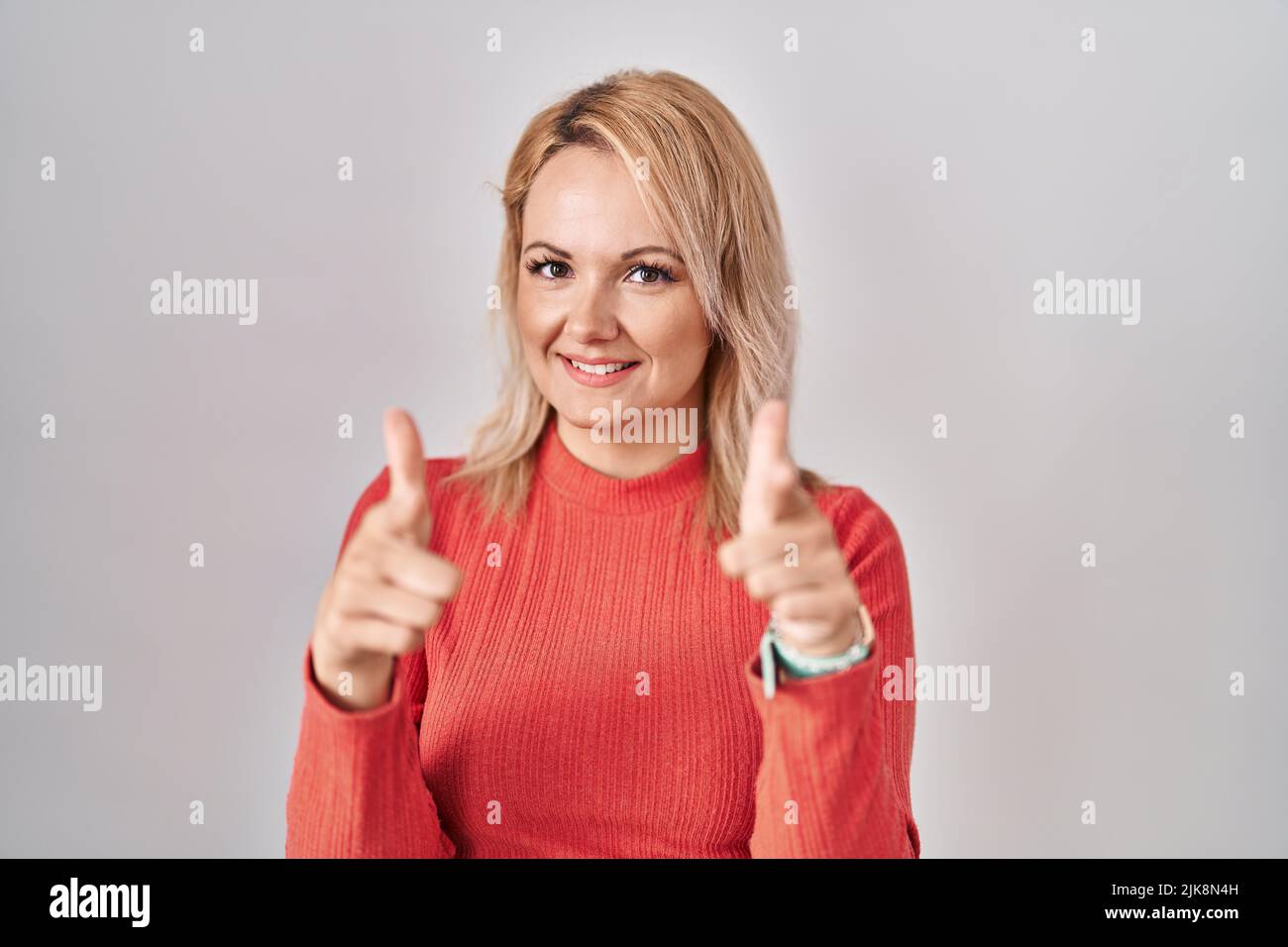 Blonde woman standing over isolated background pointing fingers to ...