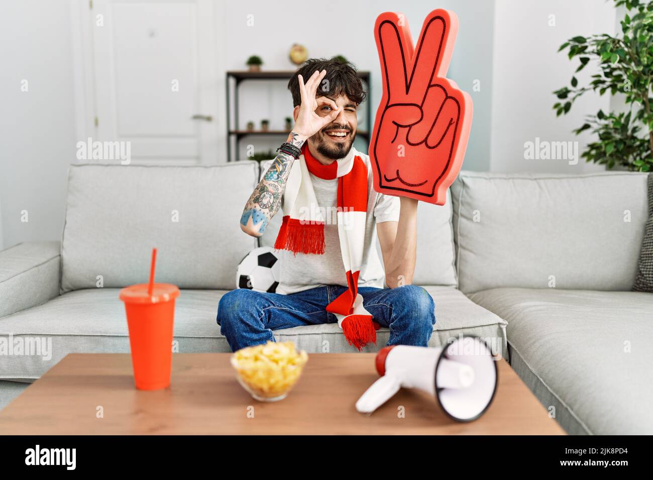 Hispanic man with beard supporting football team at home sitting on the ...