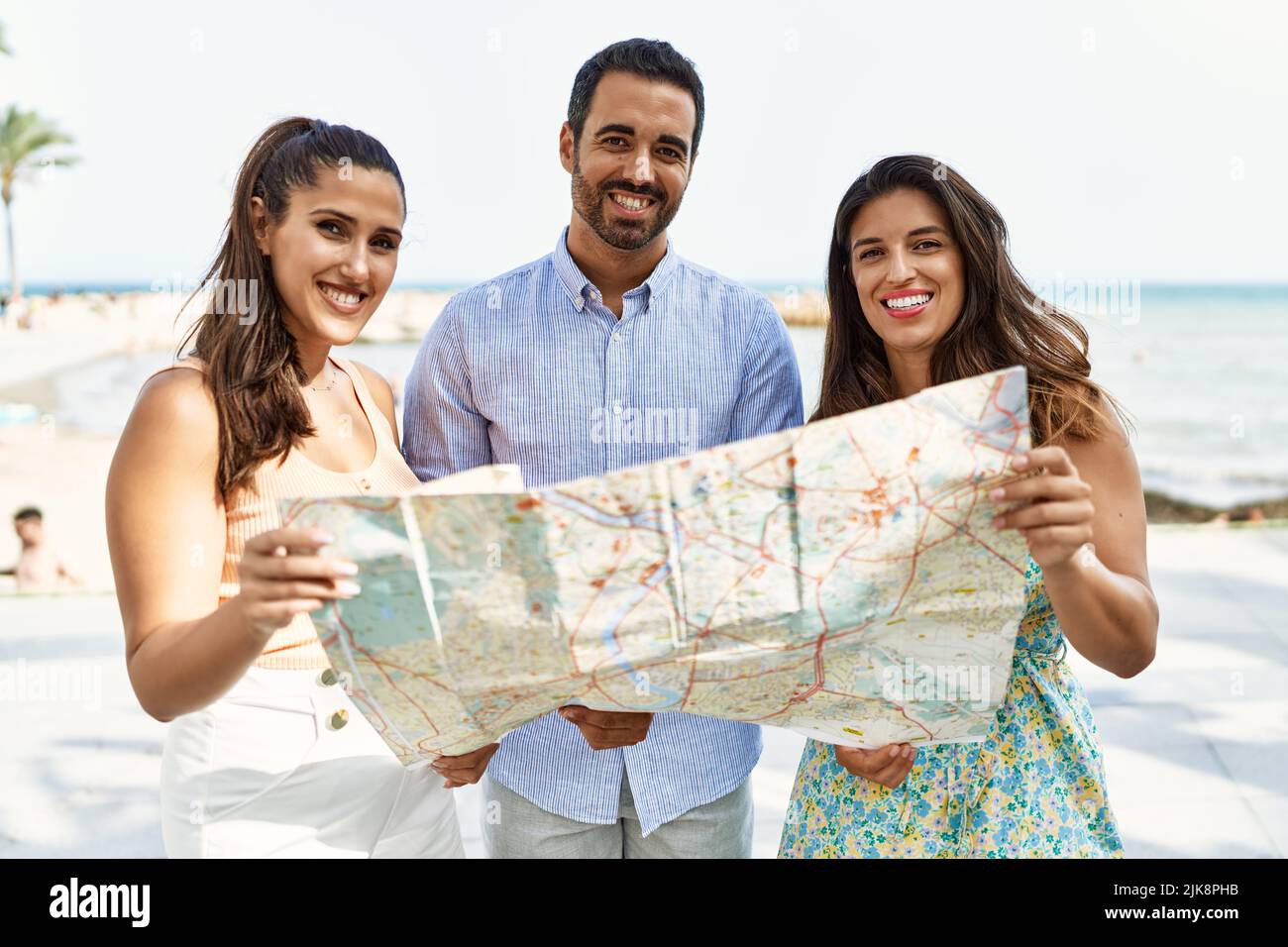 Three young hispanic friends smiling happy searching route on city map ...
