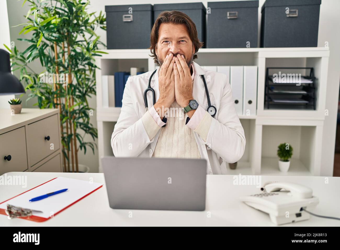 Handsome middle age doctor man working at the clinic laughing and ...