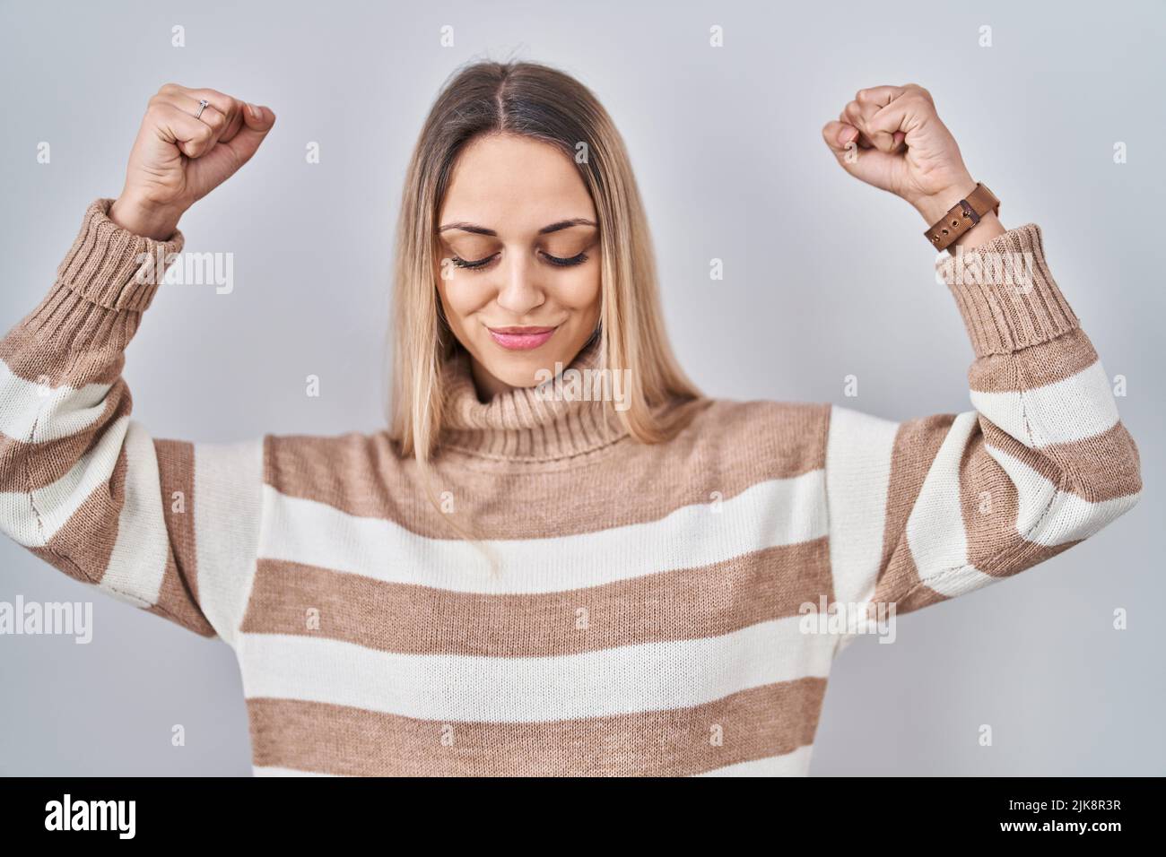 Young blonde woman wearing turtleneck sweater over isolated background ...