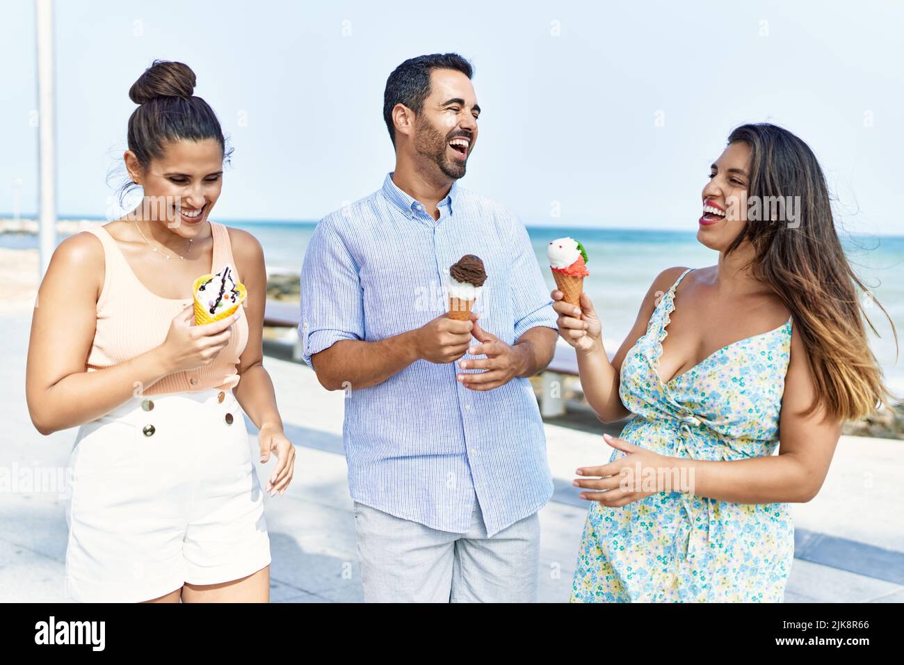 Three young hispanic friends smiling happy eating ice cream at the ...