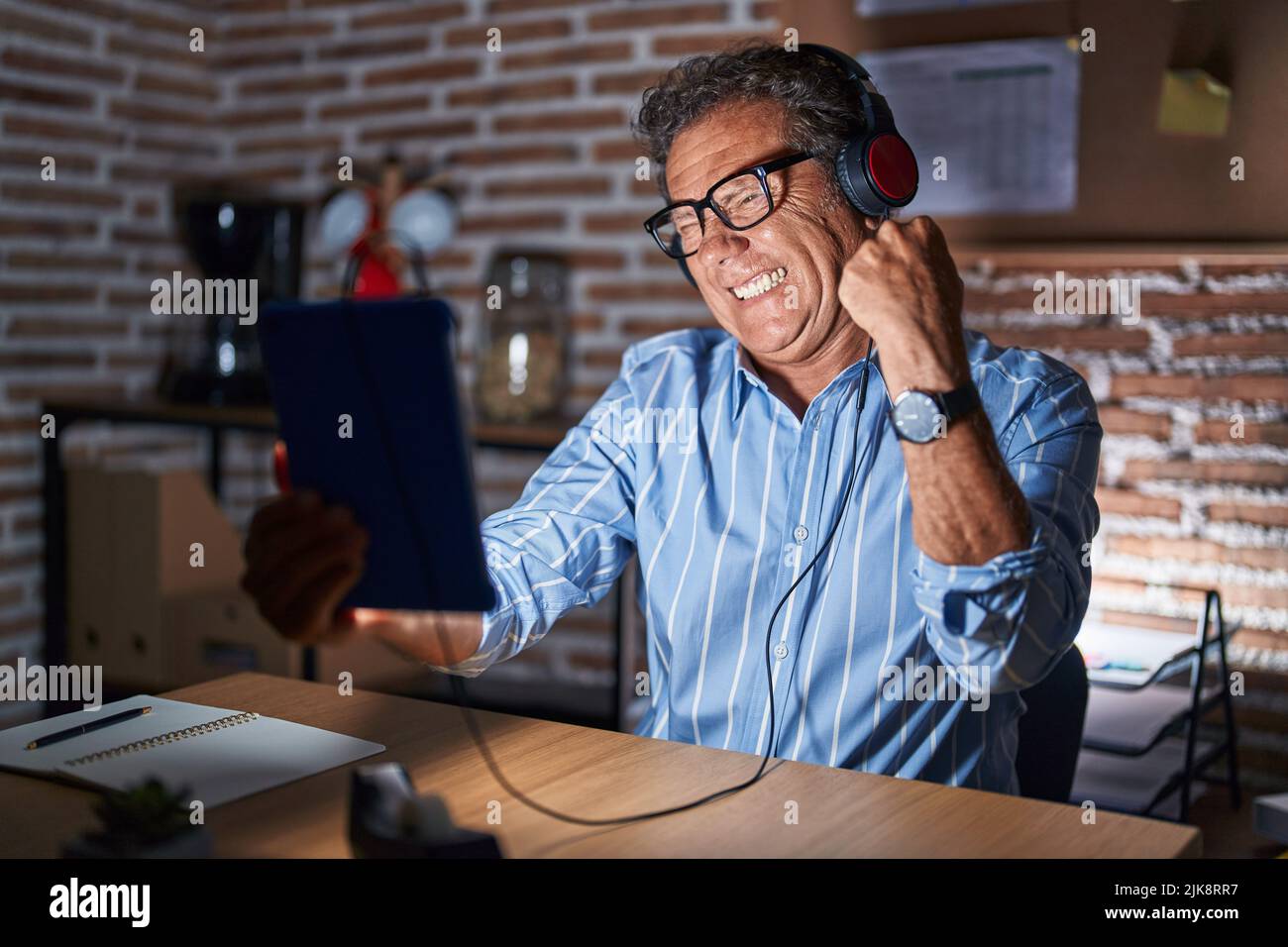 Middle age hispanic man using touchpad sitting on the table at night ...