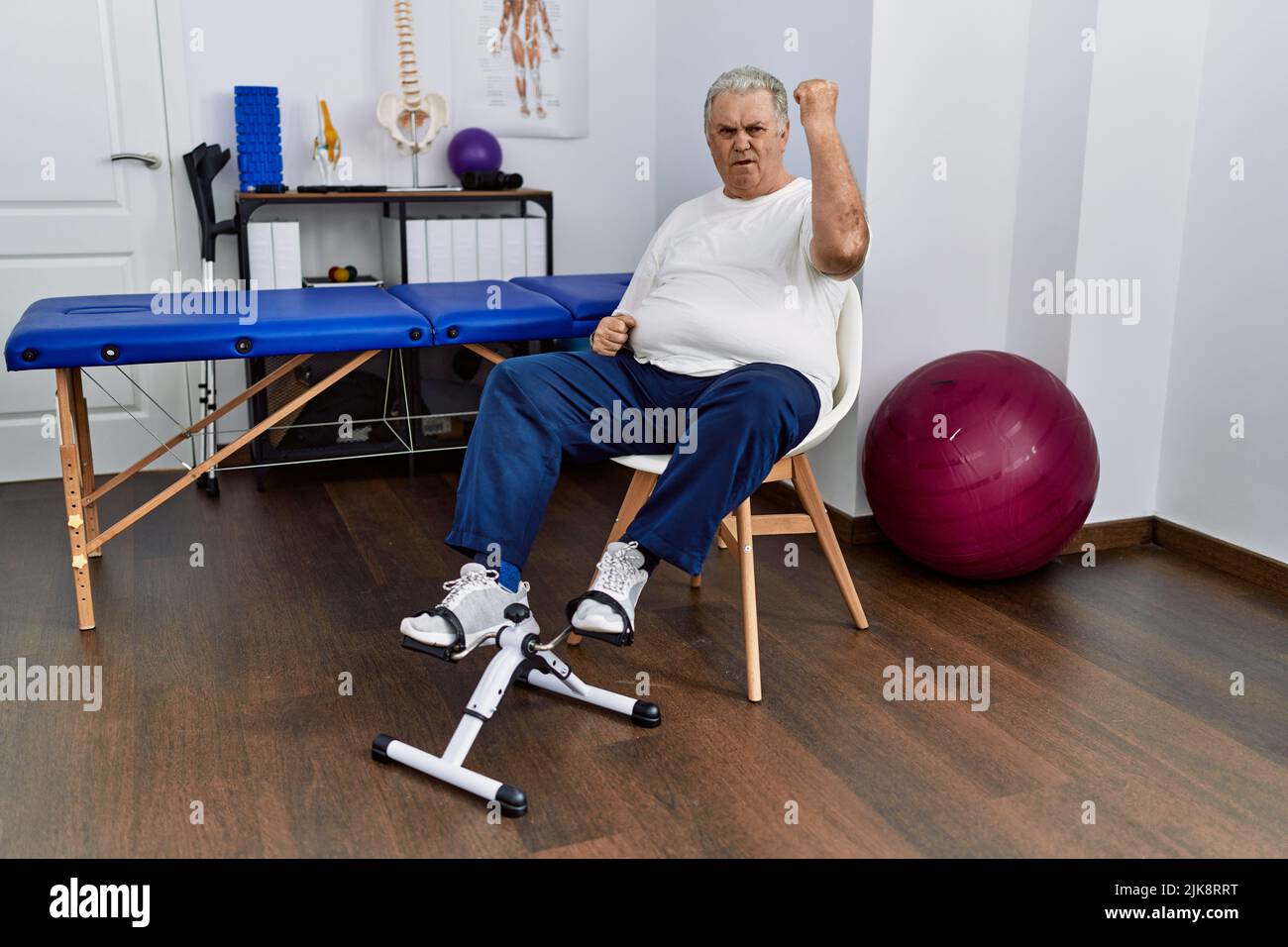 Senior caucasian man at physiotherapy clinic using pedal exerciser ...