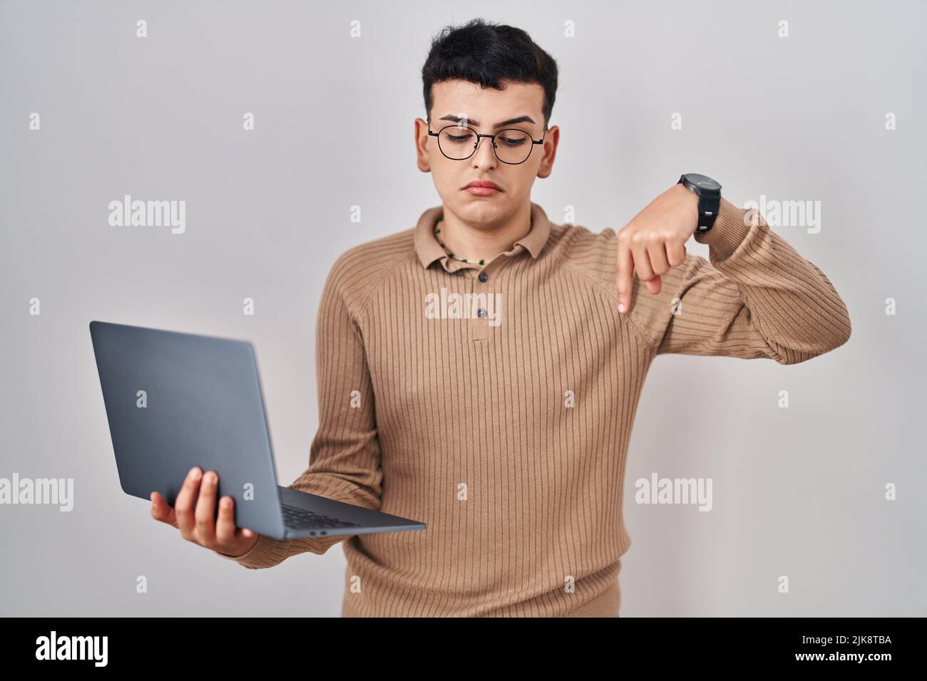 Non binary person using computer laptop pointing down looking sad and ...
