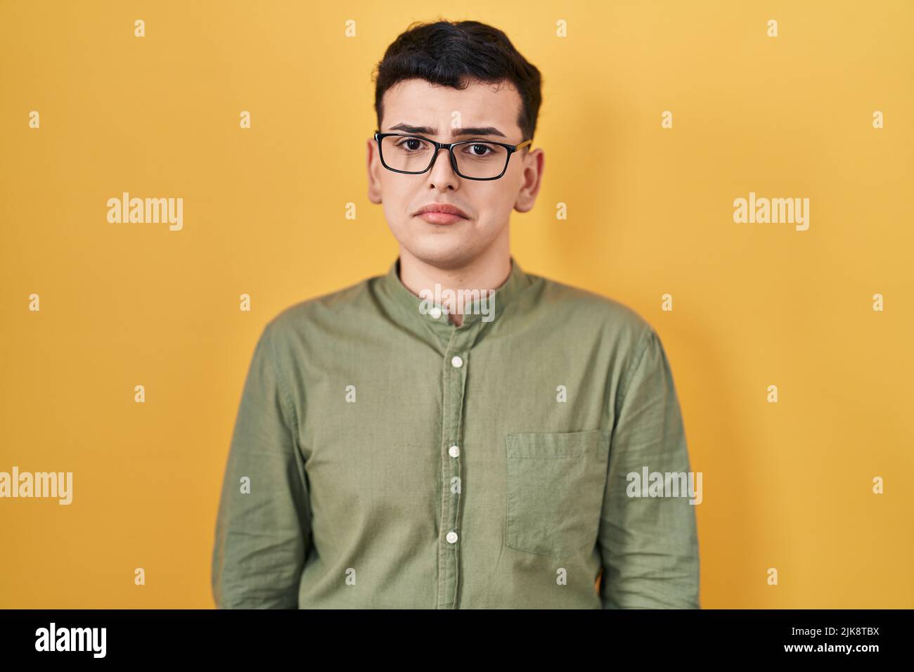 Non binary person standing over yellow background depressed and worry ...