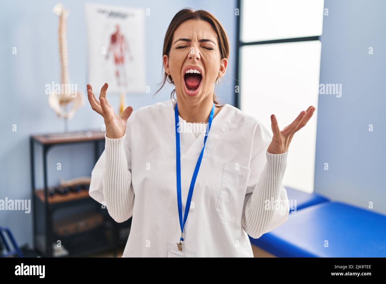 Young brunette woman working at pain recovery clinic celebrating mad ...