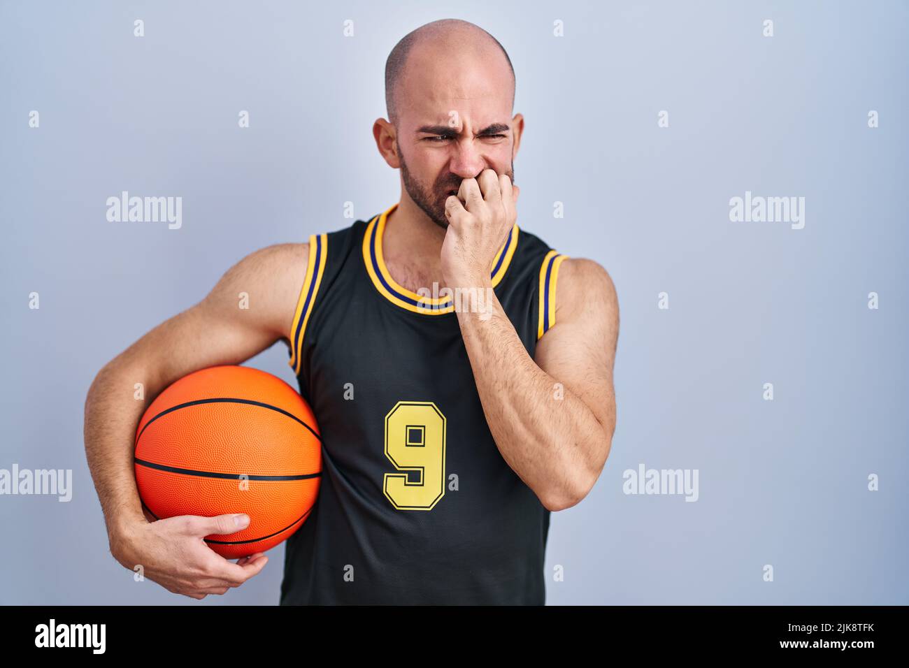 Young bald man with beard wearing basketball uniform holding ball ...