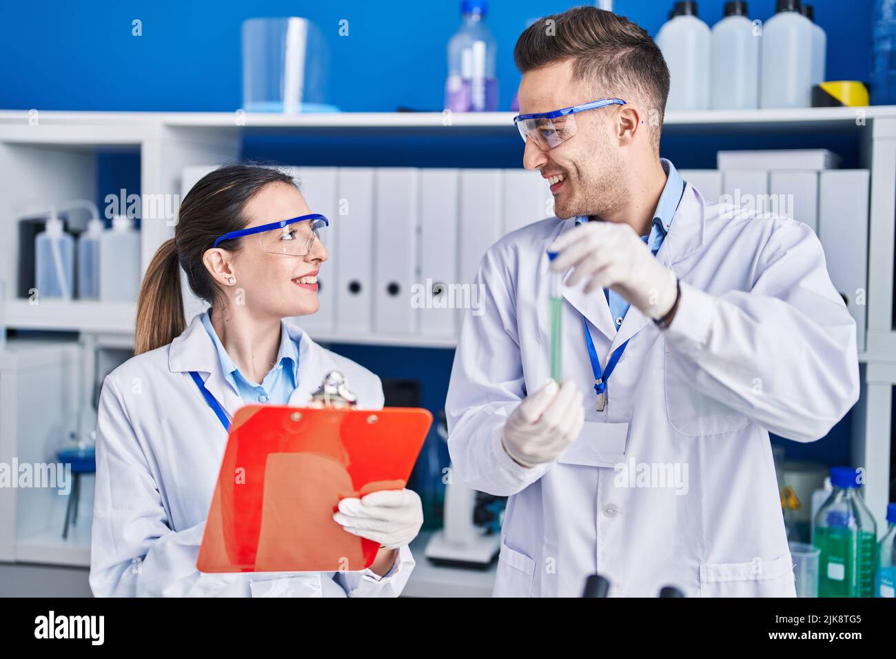 Man and woman scientists holding test tubes write on document at ...
