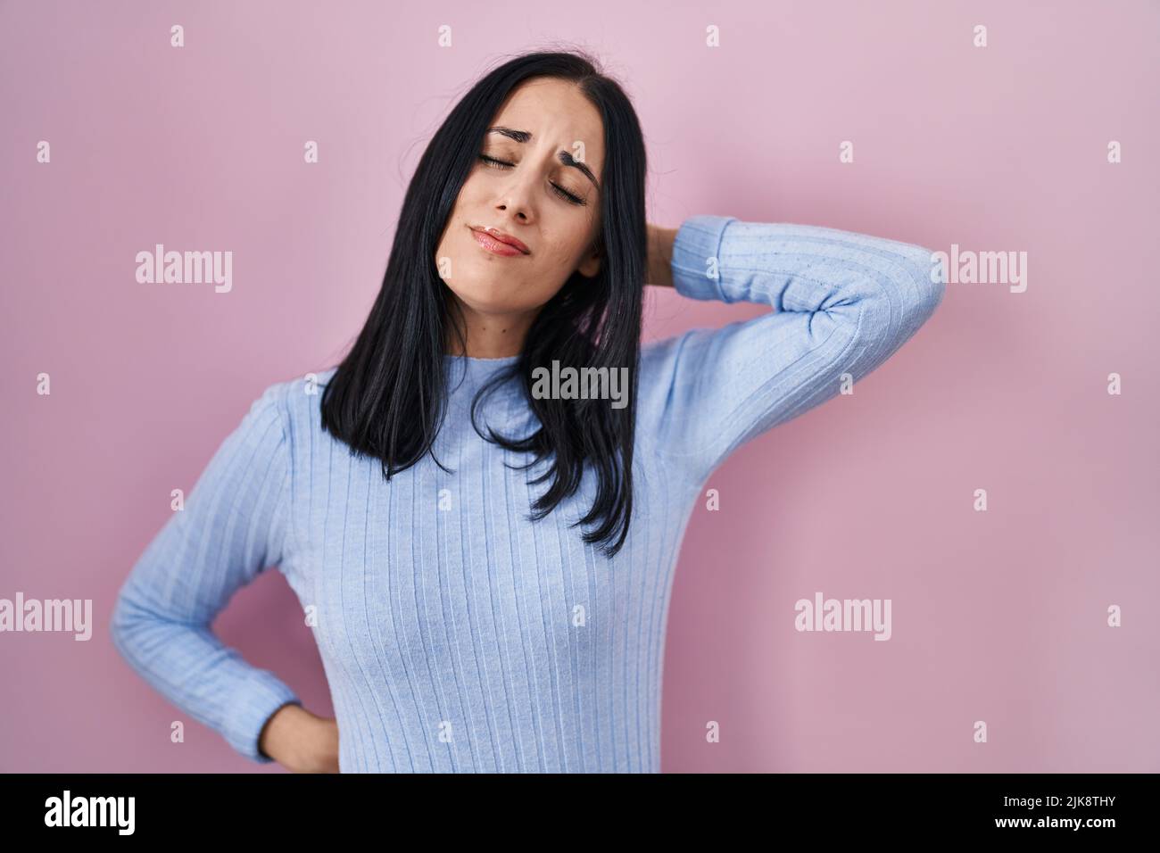 Hispanic woman standing over pink background suffering of neck ache ...