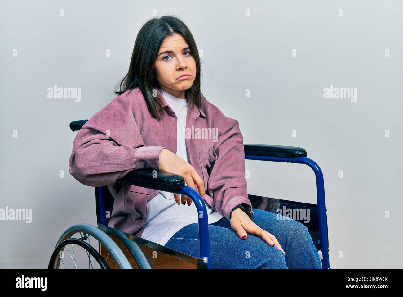 Young brunette woman sitting on wheelchair depressed and worry for distress, crying angry and ...