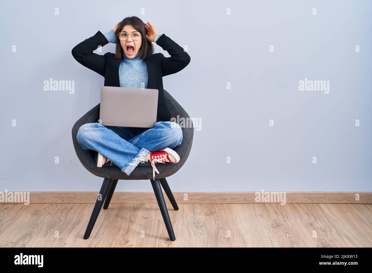 Young hispanic woman sitting on chair using computer laptop crazy and ...