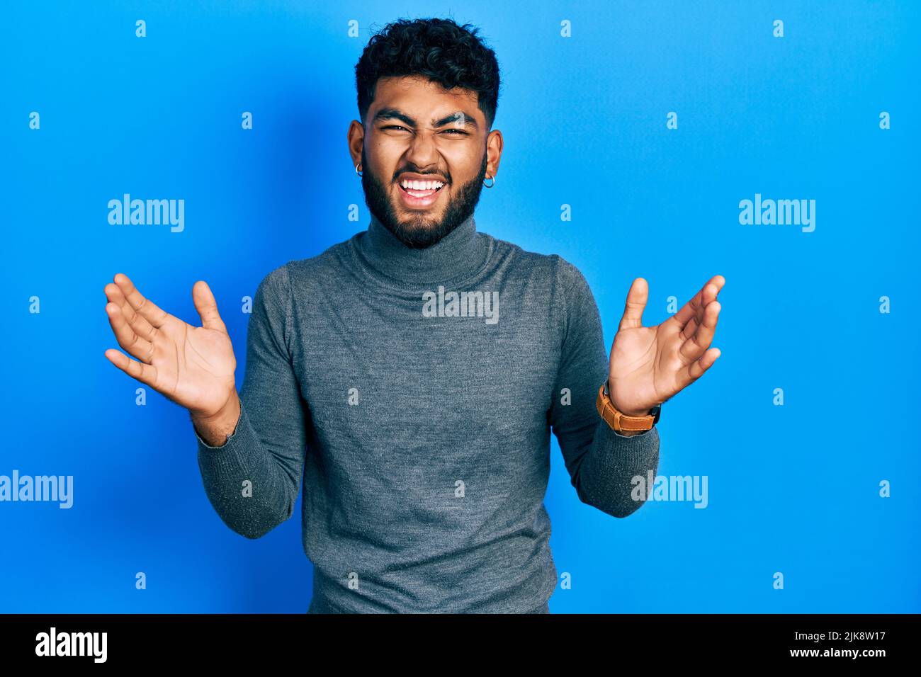 Arab man with beard wearing turtleneck sweater celebrating mad and ...