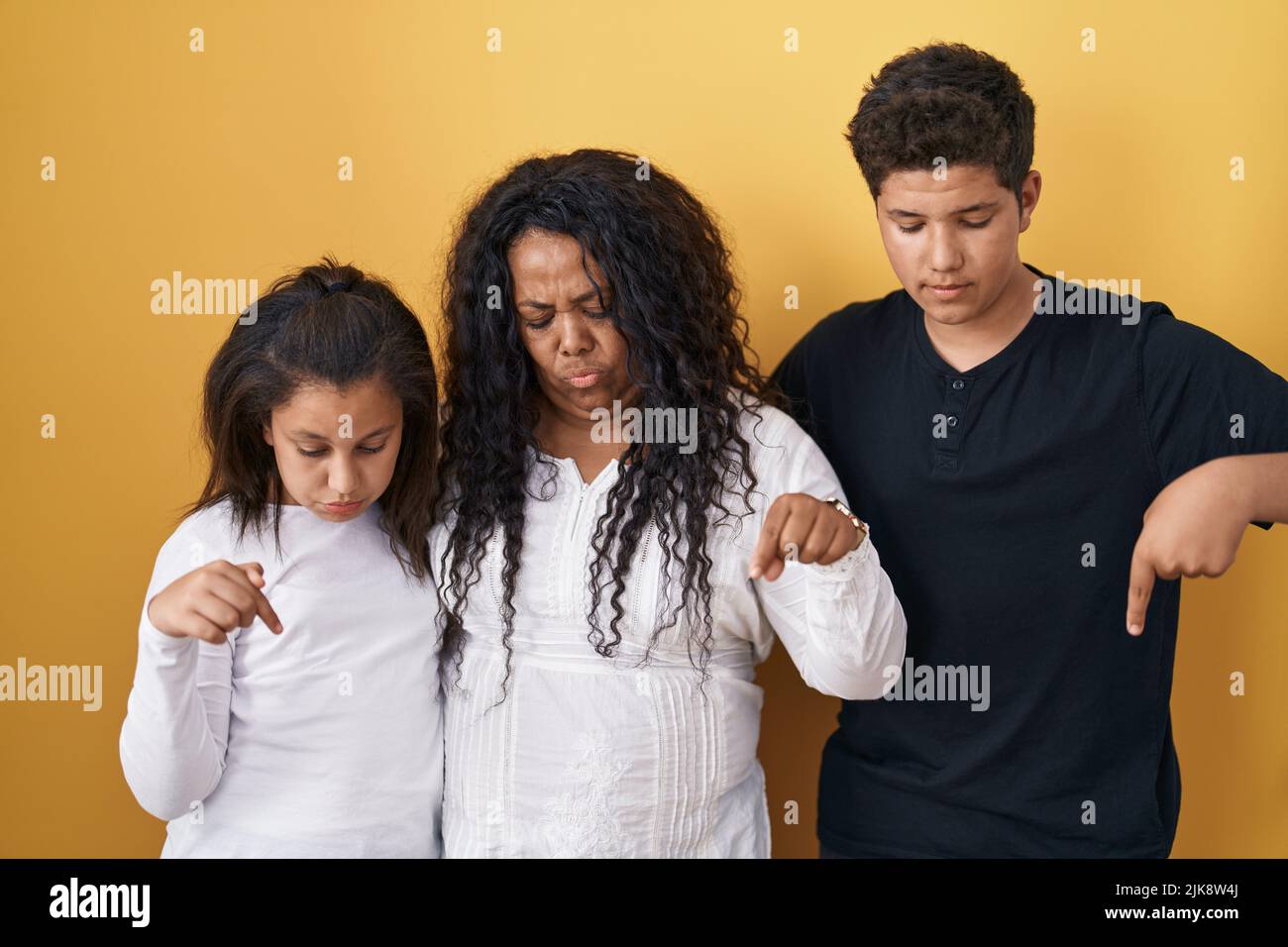 Family of mother, daughter and son standing over yellow background ...