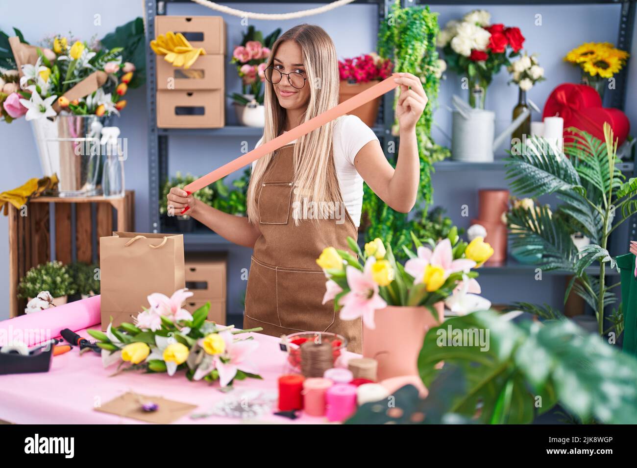 Young beautiful hispanic woman florist make bouquet of flowers holding ...
