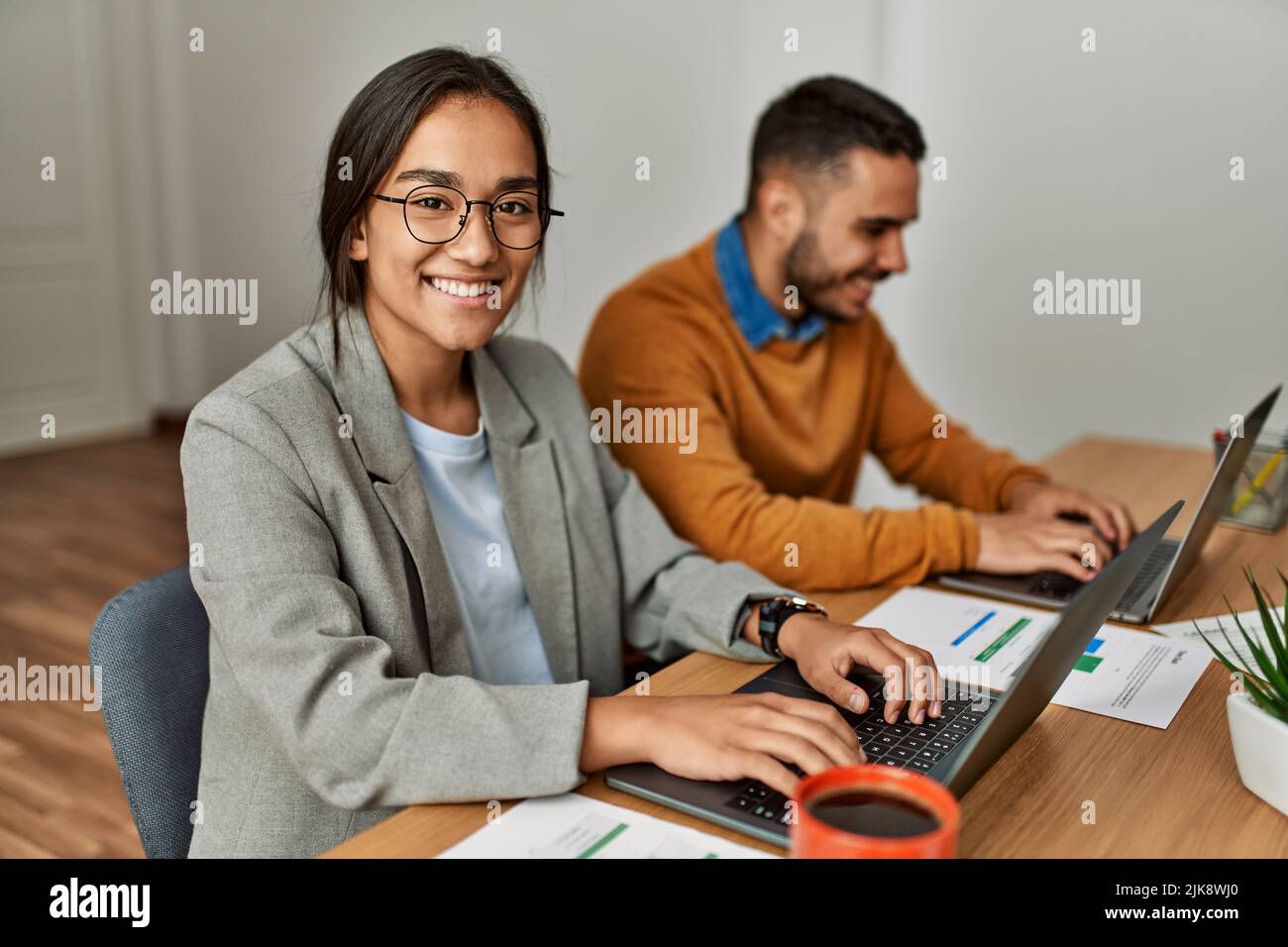 Two business workers smiling happy working sitting on desk at the ...