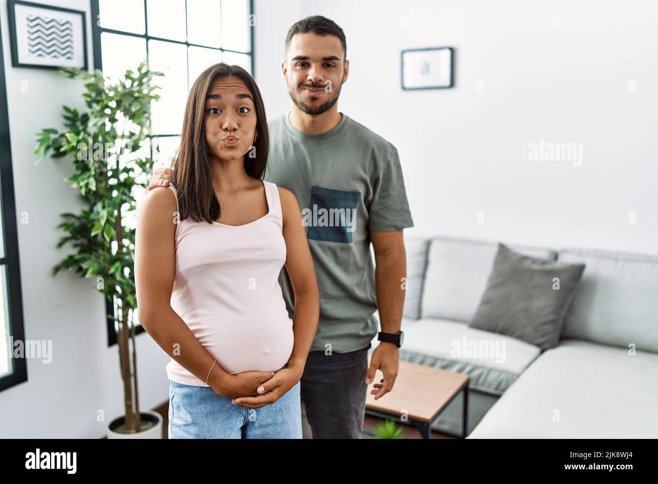 Young interracial couple expecting a baby, touching pregnant belly ...