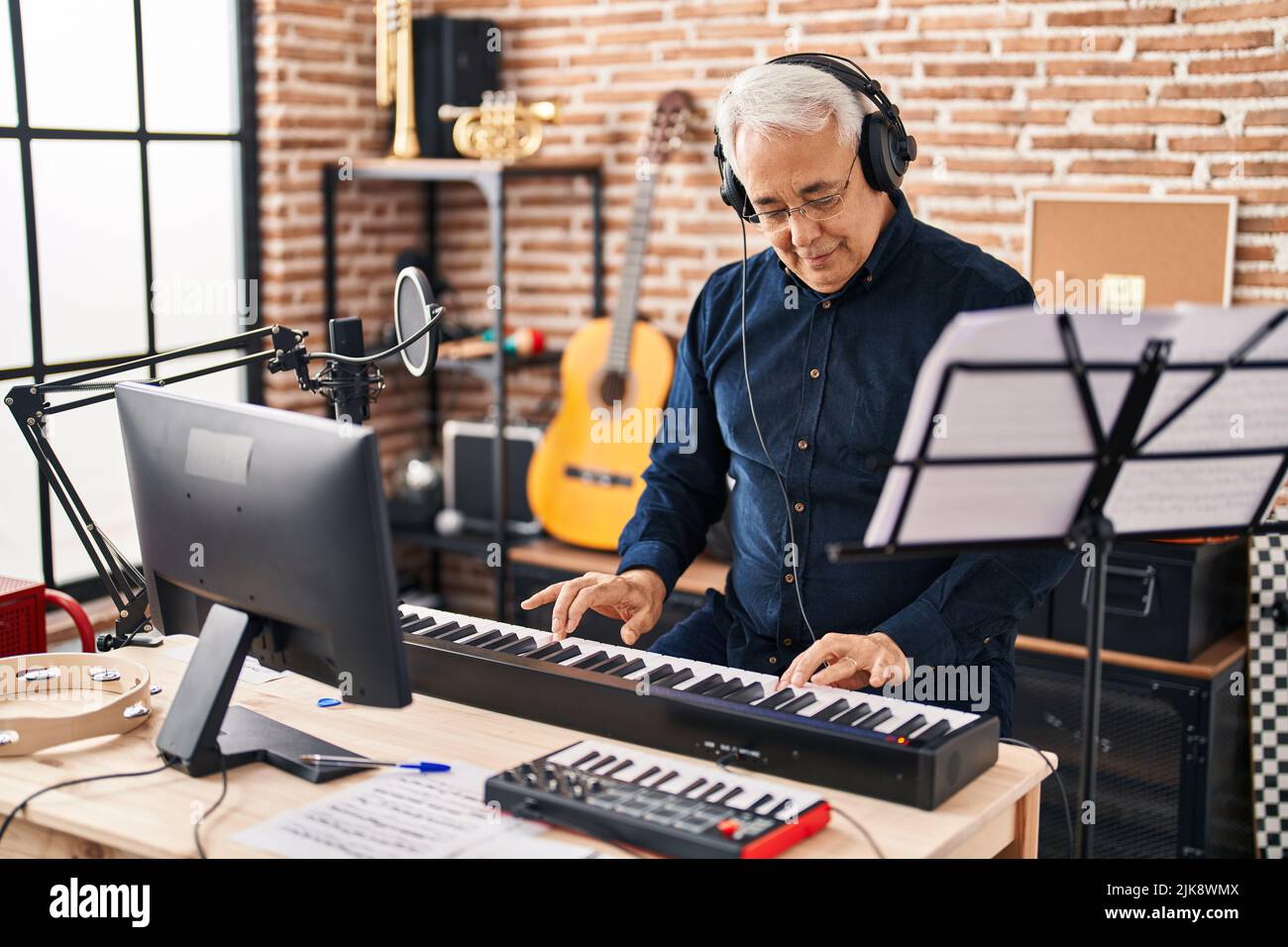 Senior man musician playing piano keyboard at music studio Stock Photo ...