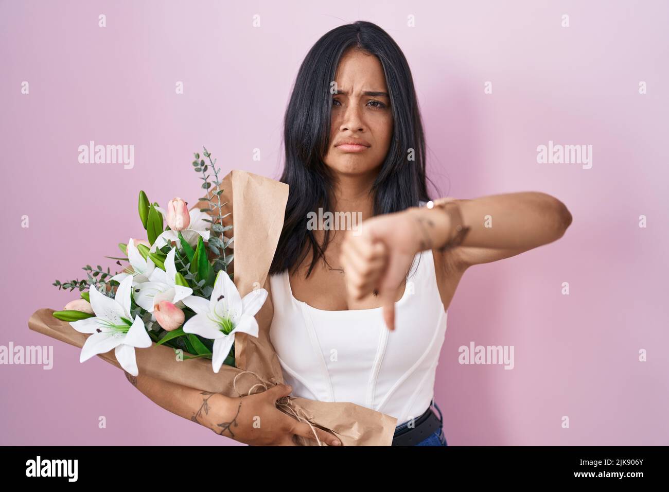 Brunette woman holding bouquet of white flowers looking unhappy and ...