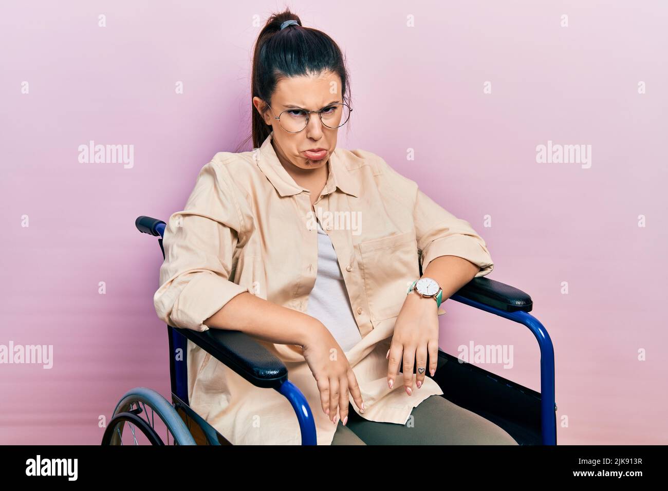Young hispanic woman sitting on wheelchair depressed and worry for distress, crying angry and ...