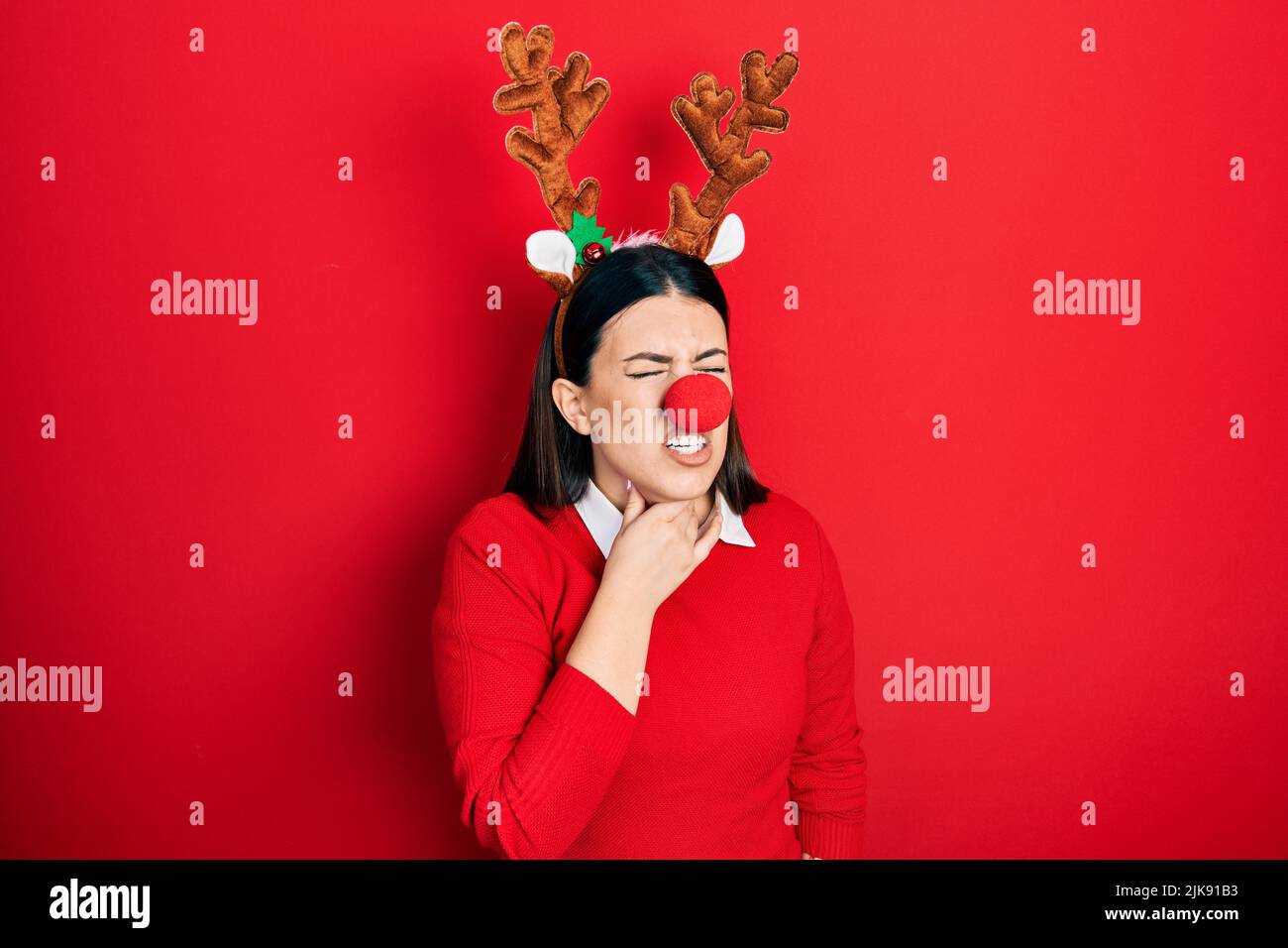 Young Hispanic Woman Wearing Deer Christmas Hat And Red Nose Touching