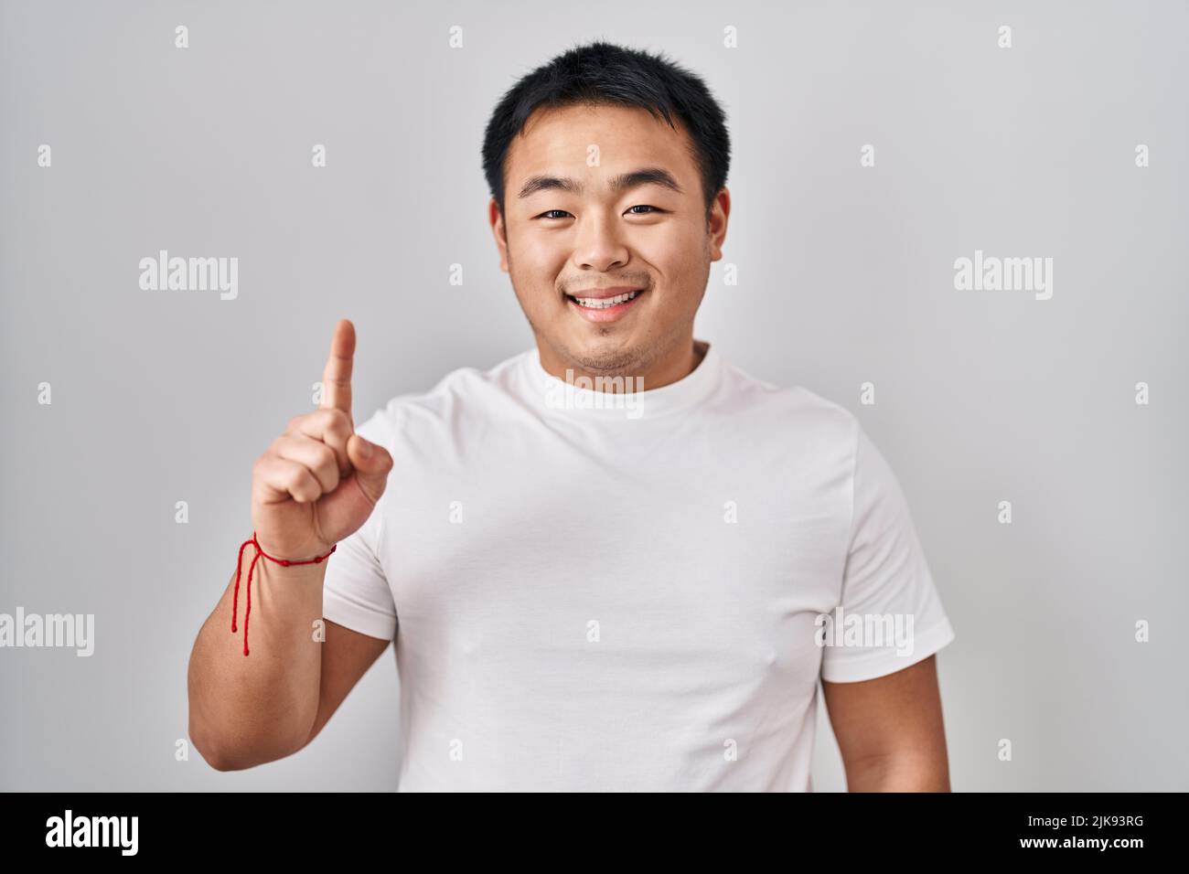 Young chinese man standing over white background showing and pointing ...
