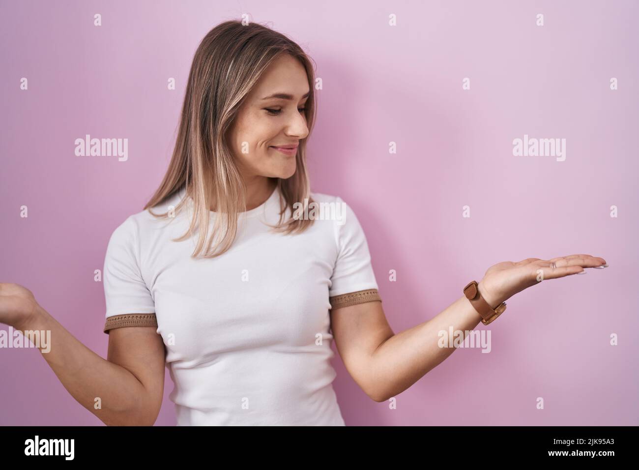 Blonde caucasian woman standing over pink background smiling showing ...
