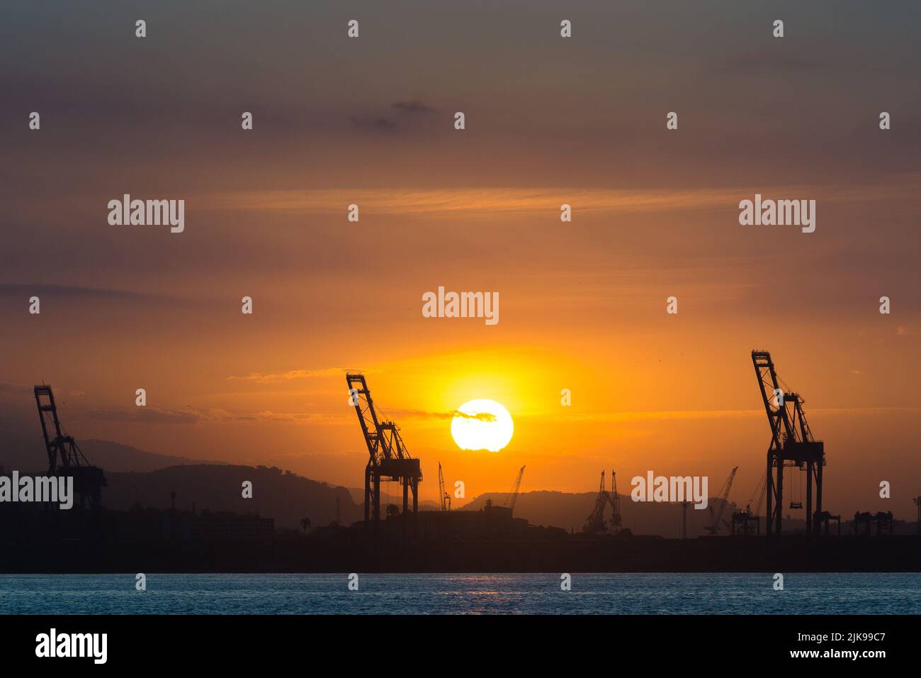 Industrial Cranes in the Horizon With Sun Setting Behind Stock Photo ...