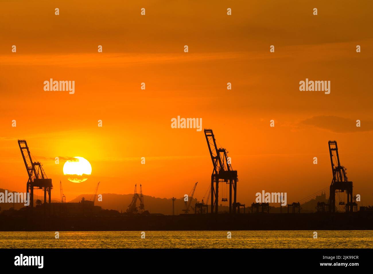 Industrial Cranes in the Horizon With Sun Setting Behind Stock Photo ...