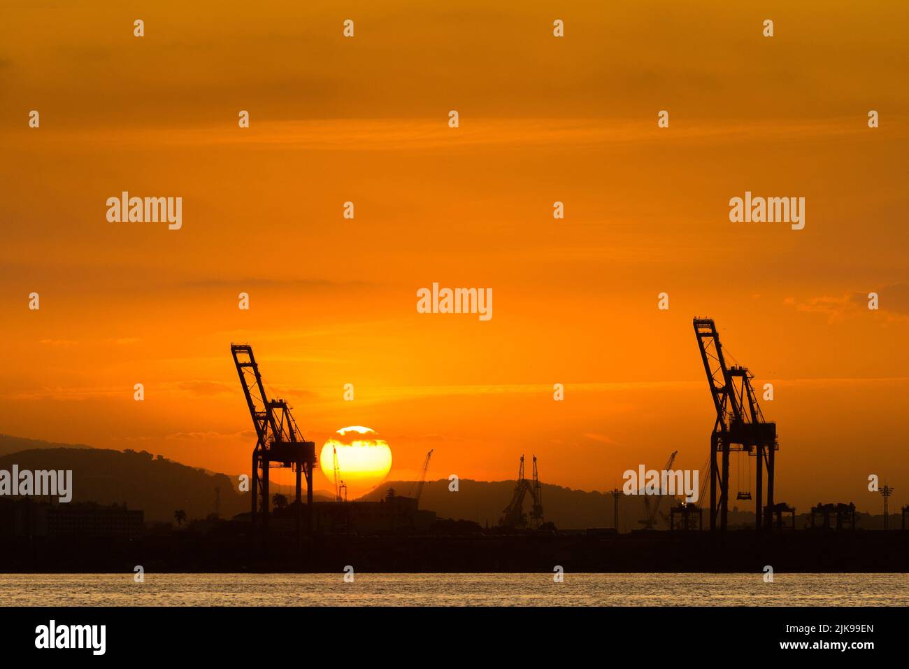 Industrial Cranes in the Horizon With Sun Setting Behind Stock Photo ...