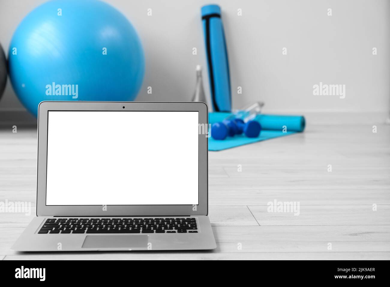 Modern laptop on floor in light room with sports equipment Stock Photo ...