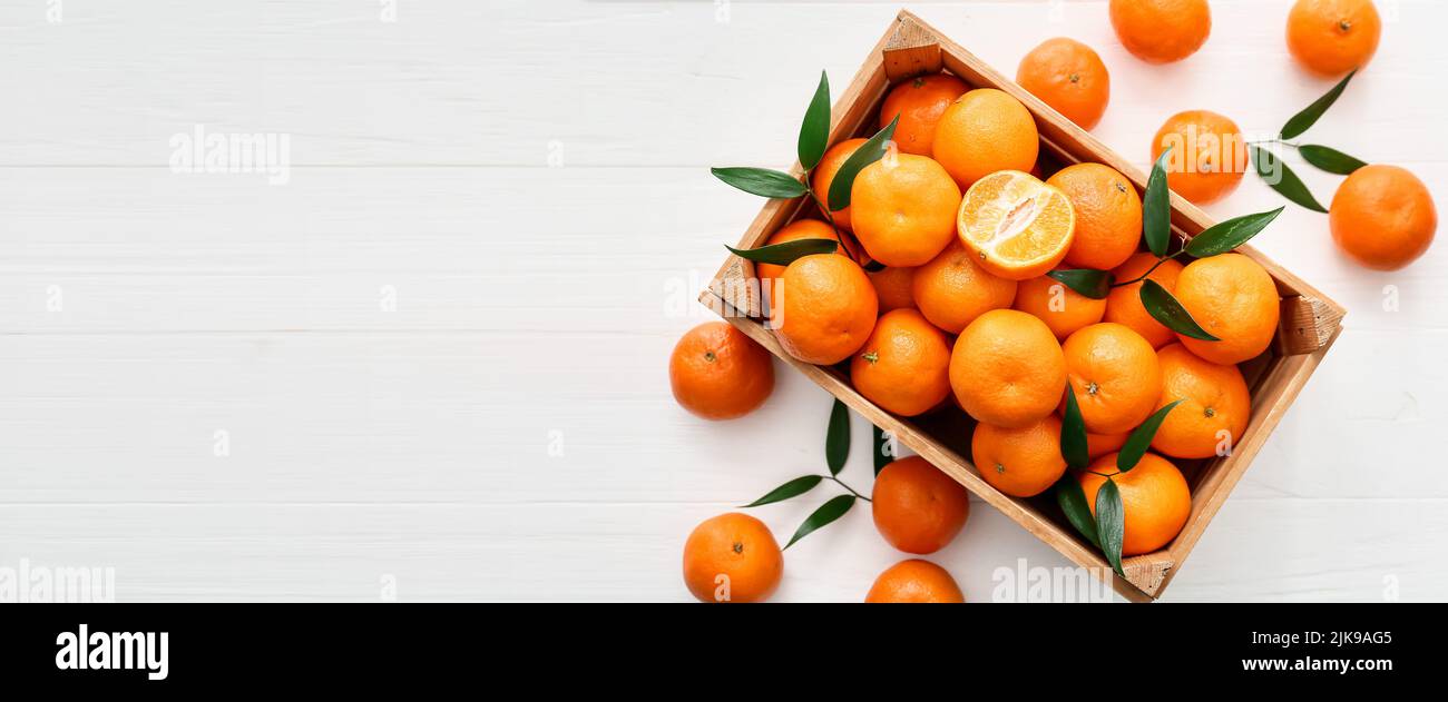 Box of sweet tangerines on white wooden background with space for text ...