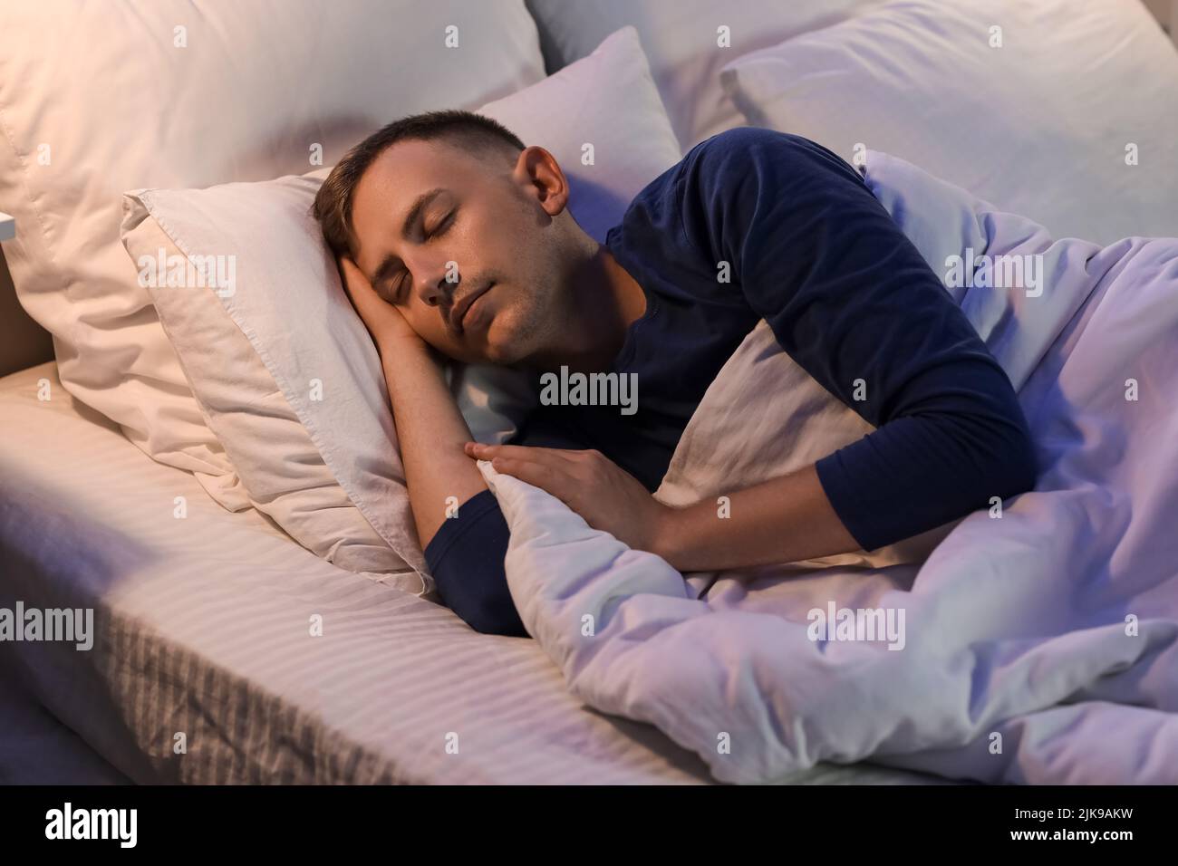 Handsome young man sleeping in bedroom at night Stock Photo - Alamy