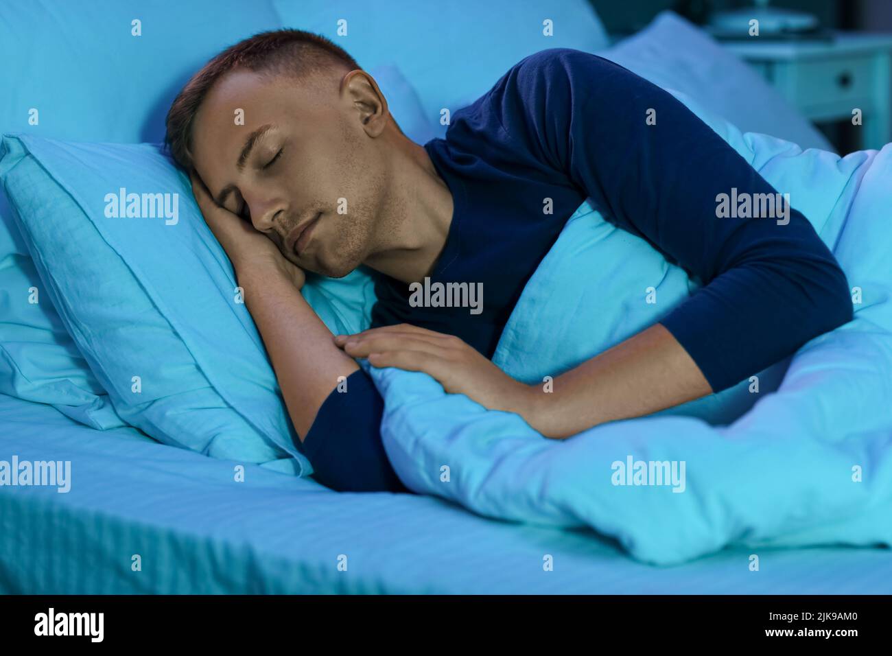 Handsome young man sleeping in bedroom at night Stock Photo - Alamy
