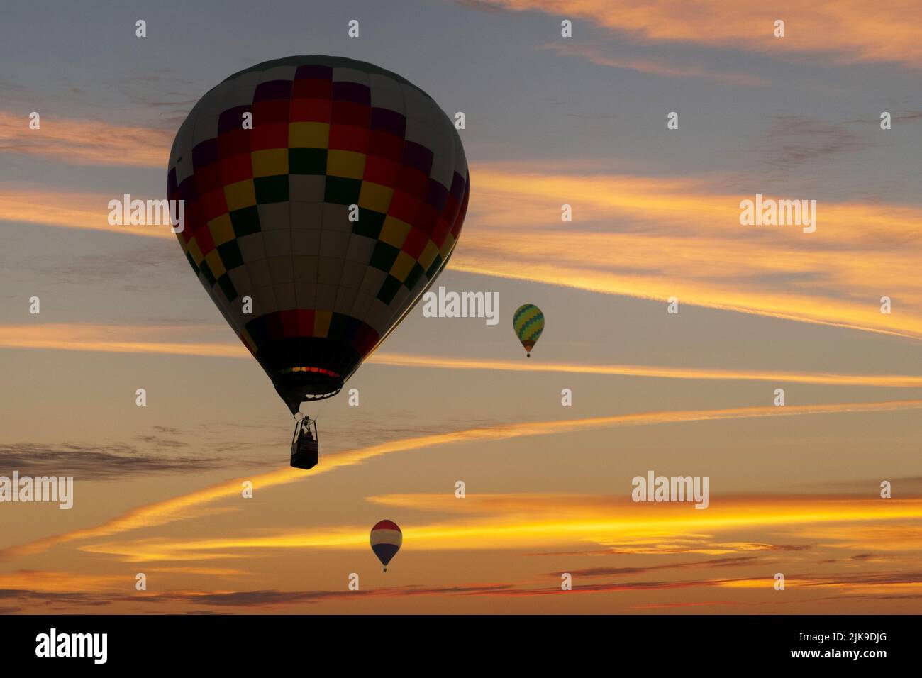 Hot air balloons are silhouetted against the sky at sunset in a ...