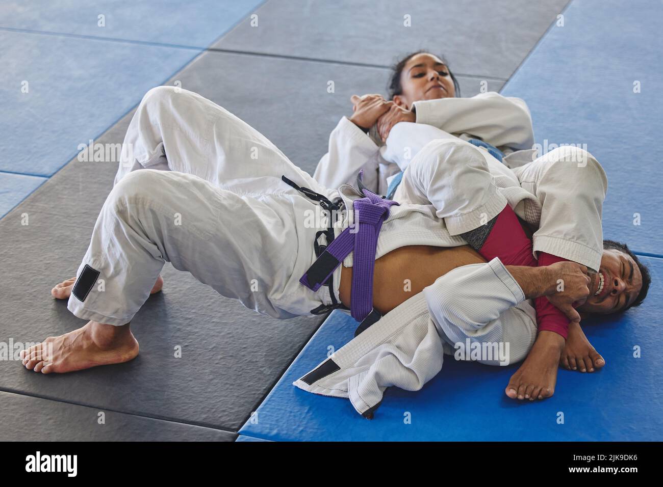 Shes got the upper hand. Full length shot of two young martial artists practicing jiu jitsu in ...