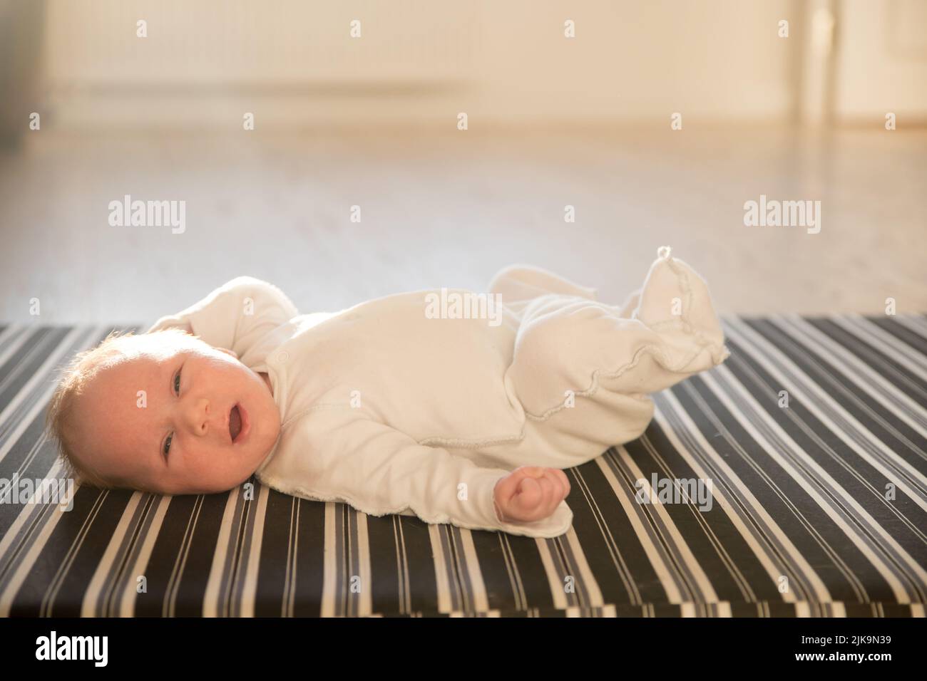 A little yawning newborn baby lying on his back Stock Photo - Alamy