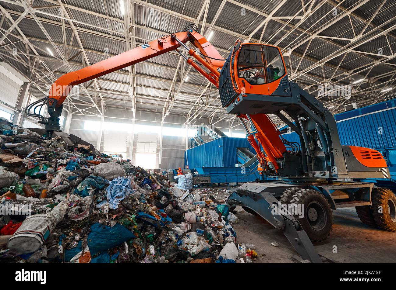 Excavator grabs trash in warehouse of waste processing plant Stock ...